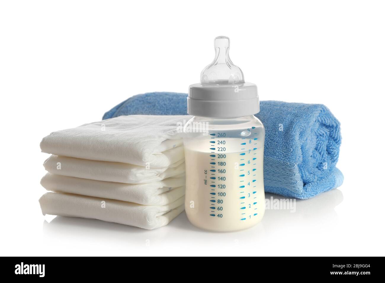 Baby bottle with milk, pile of diapers and soft towel isolated on white ...