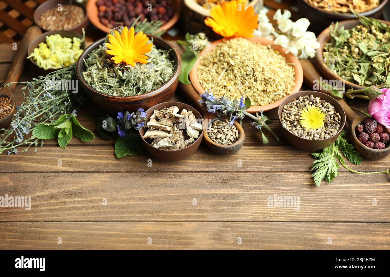 Herb selection and fresh flowers in bowls on wooden background Stock ...