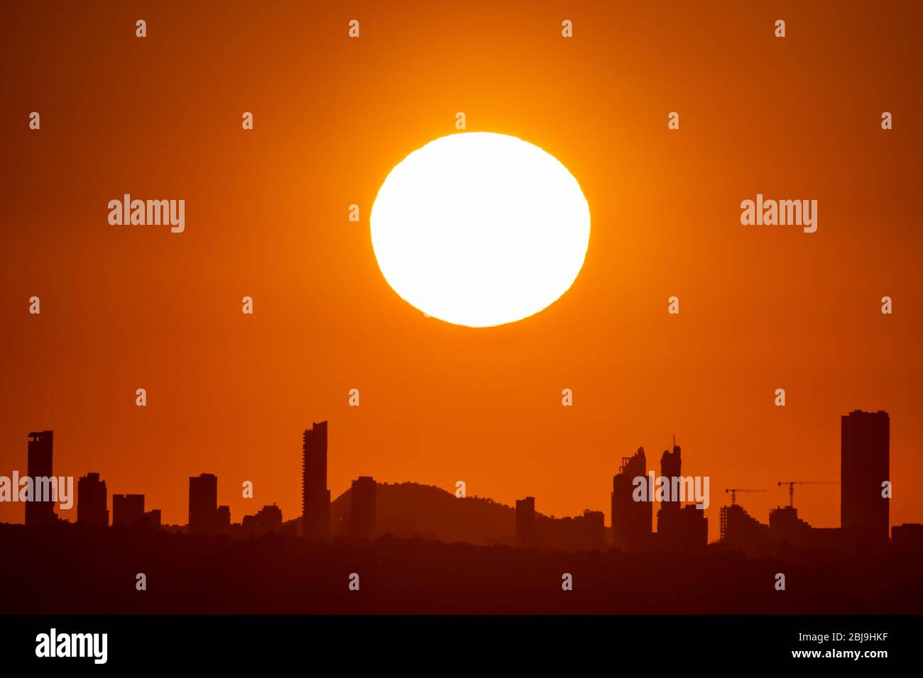 Huge sun and sunset over Benidorm city skyline silhouette Stock Photo ...