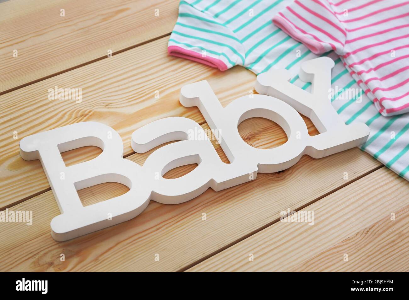 Word baby with clothes on wooden background Stock Photo - Alamy