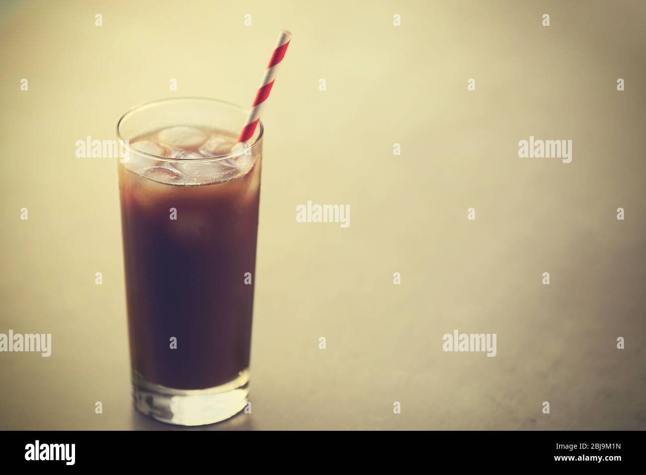 Iced coffee with straw on gray table Stock Photo - Alamy