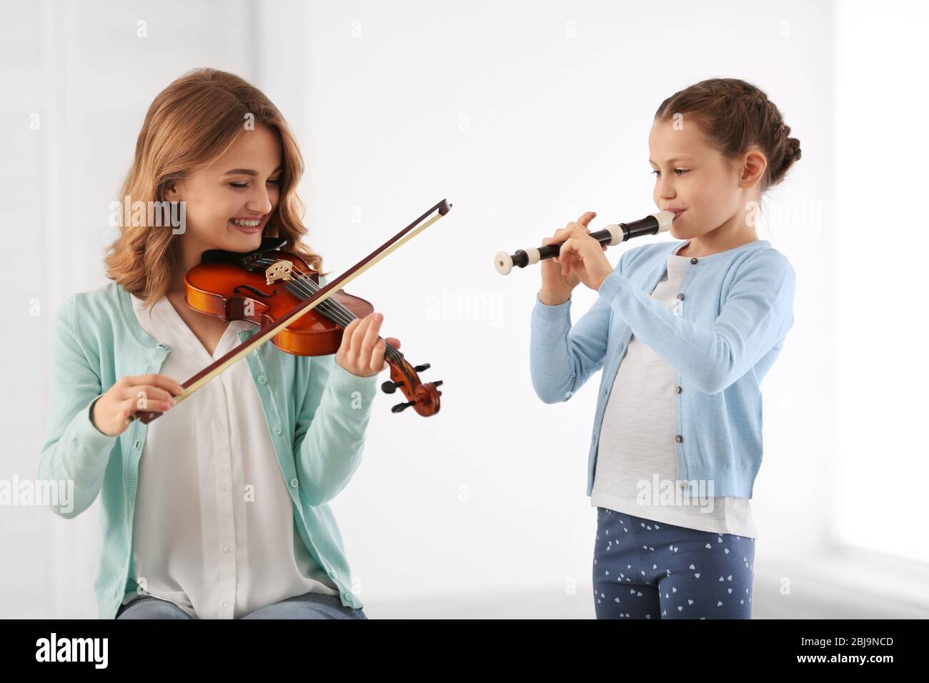 Two girls playing violin and flute on light background Stock Photo - Alamy