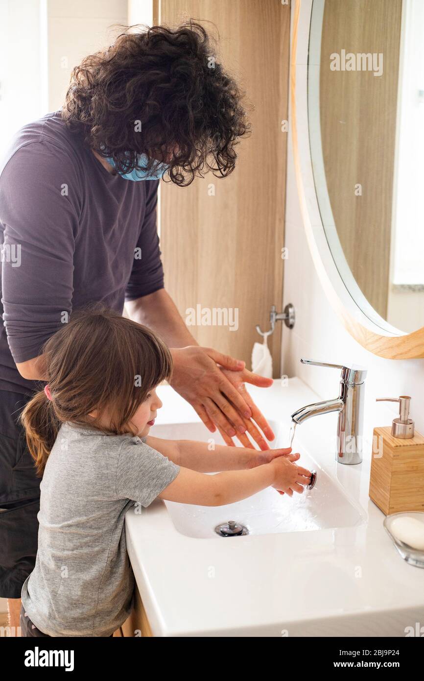Caucasian father wearing face mask to avoid contagion teaching little ...