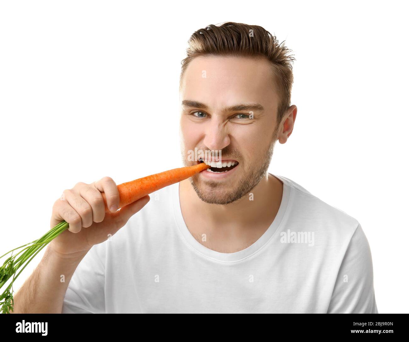 Handsome man eating carrot, isolated on white Stock Photo - Alamy