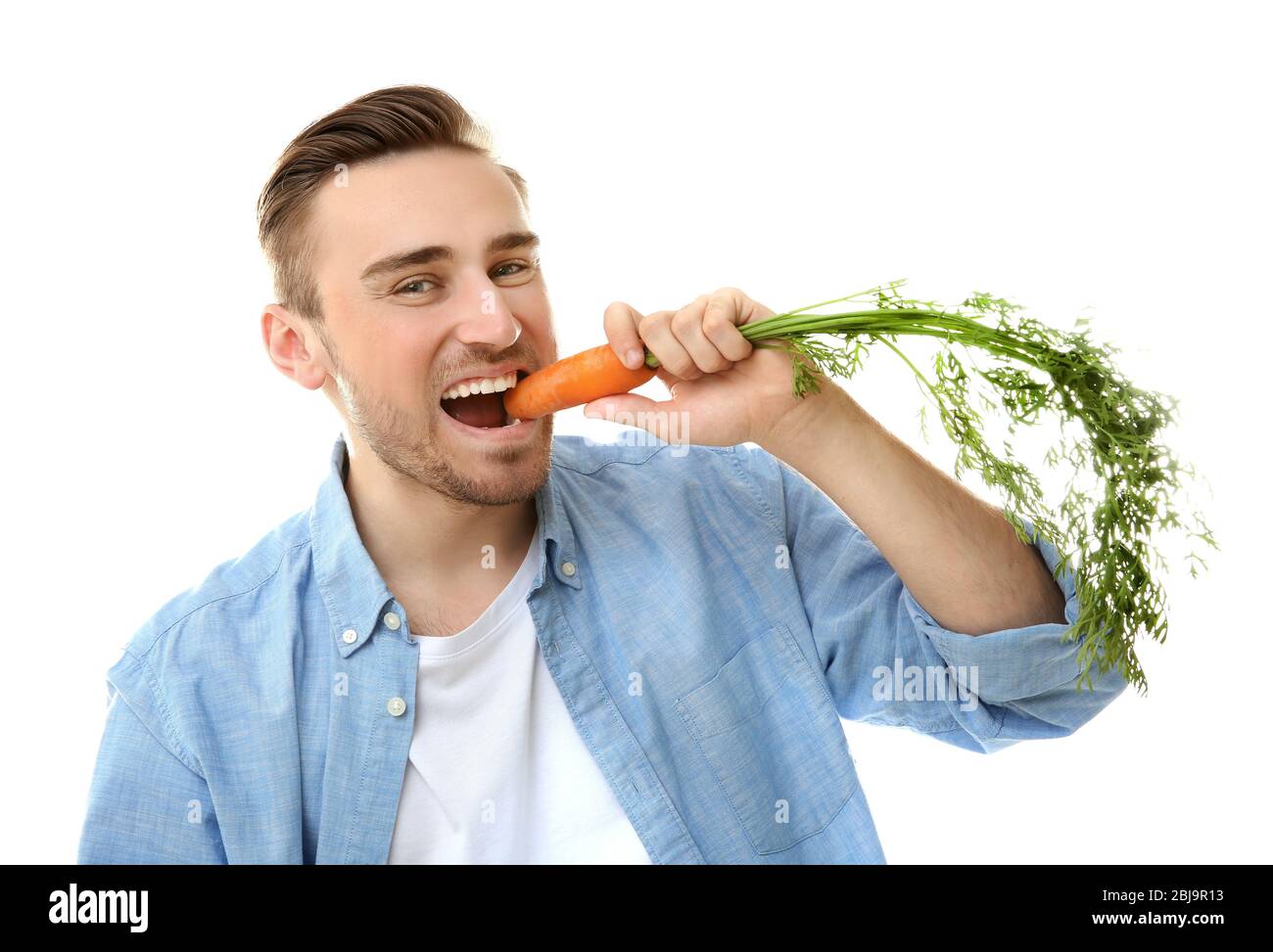 Handsome man eating carrot, isolated on white Stock Photo - Alamy