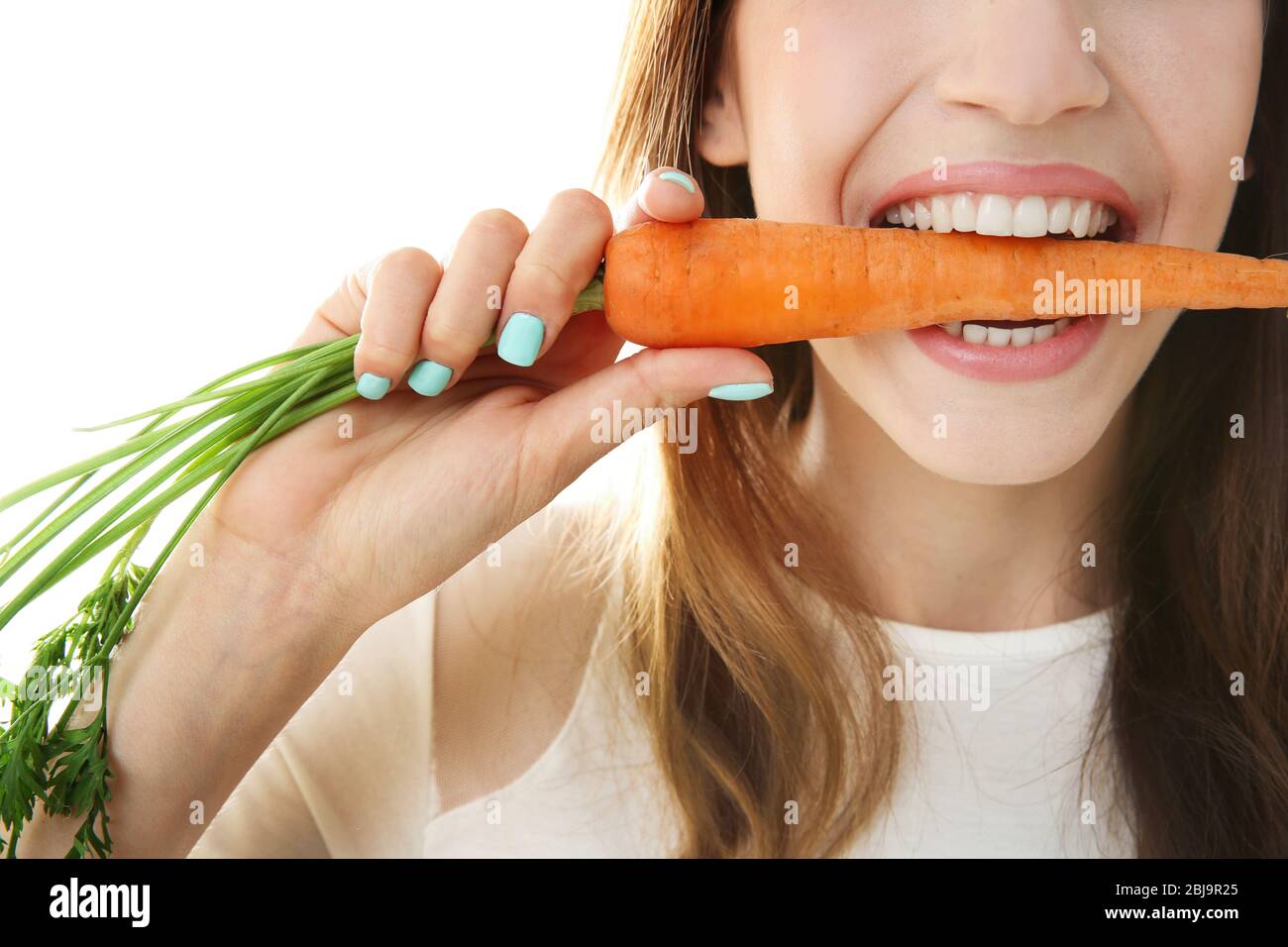 Beautiful girl eating carrot, isolated on white Stock Photo - Alamy