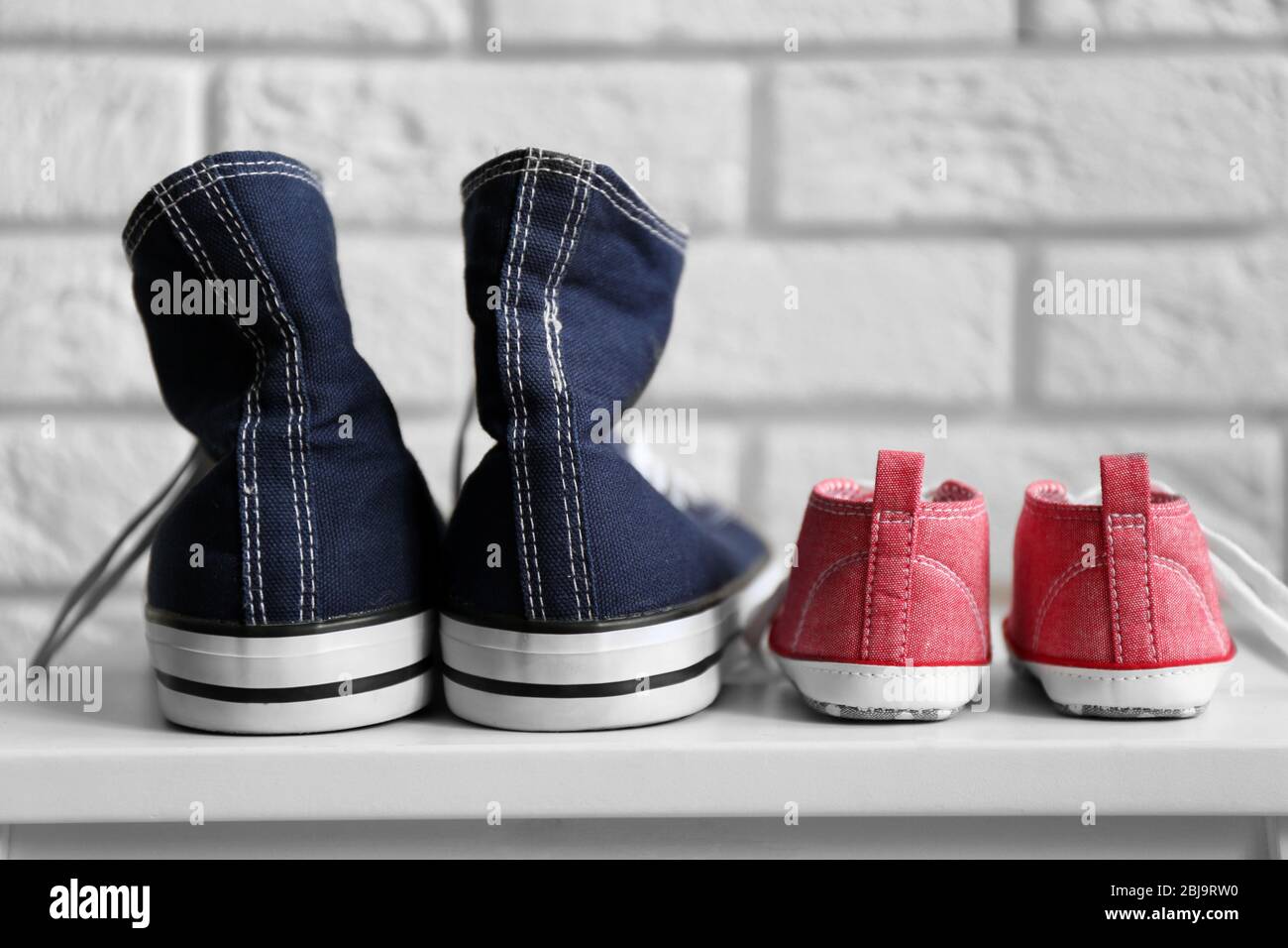Big and small shoes on wooden table Stock Photo - Alamy