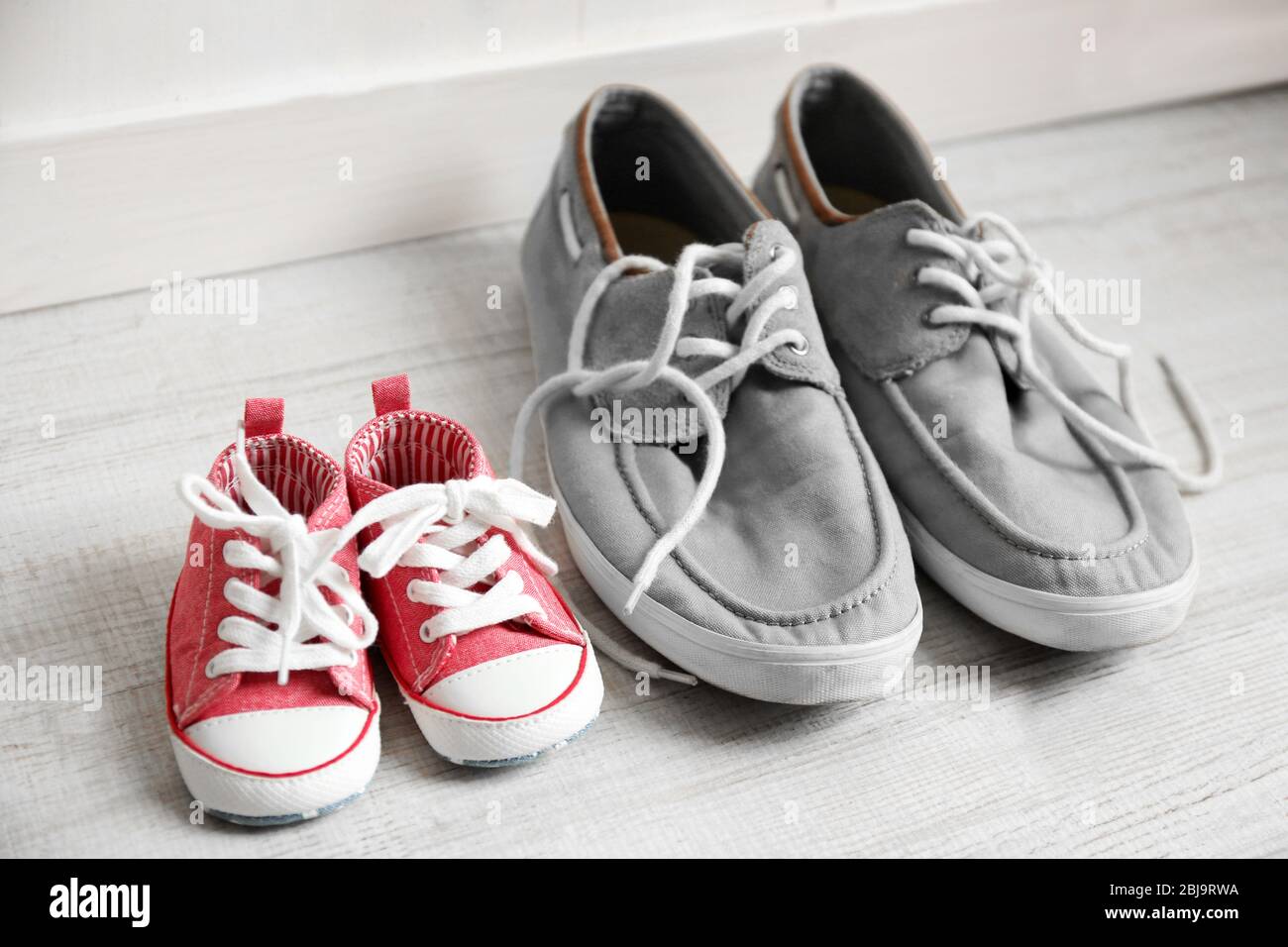 Big and small shoes on wooden floor Stock Photo - Alamy