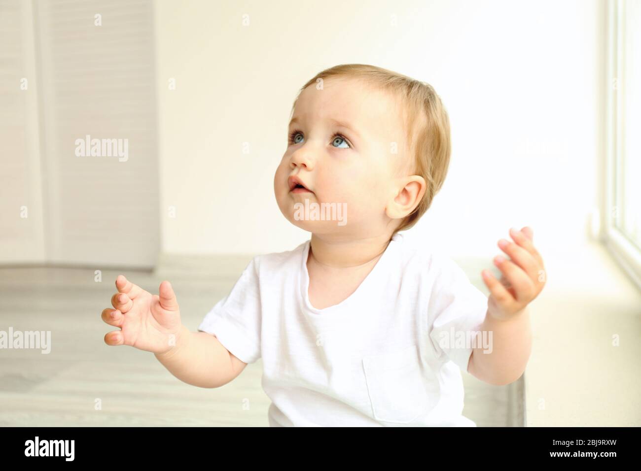 Baby sitting at window in room Stock Photo - Alamy