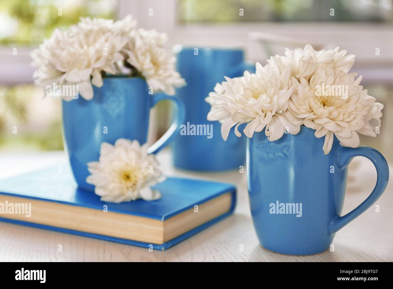 Beautiful flowers in cups on a wooden table Stock Photo - Alamy