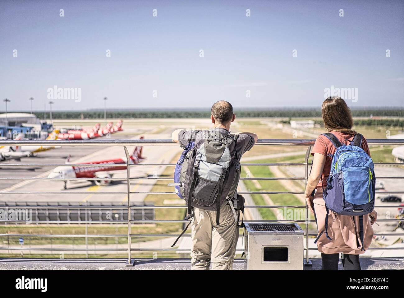 Backpackers at the airport looking at the fleet of planes parked on the ...