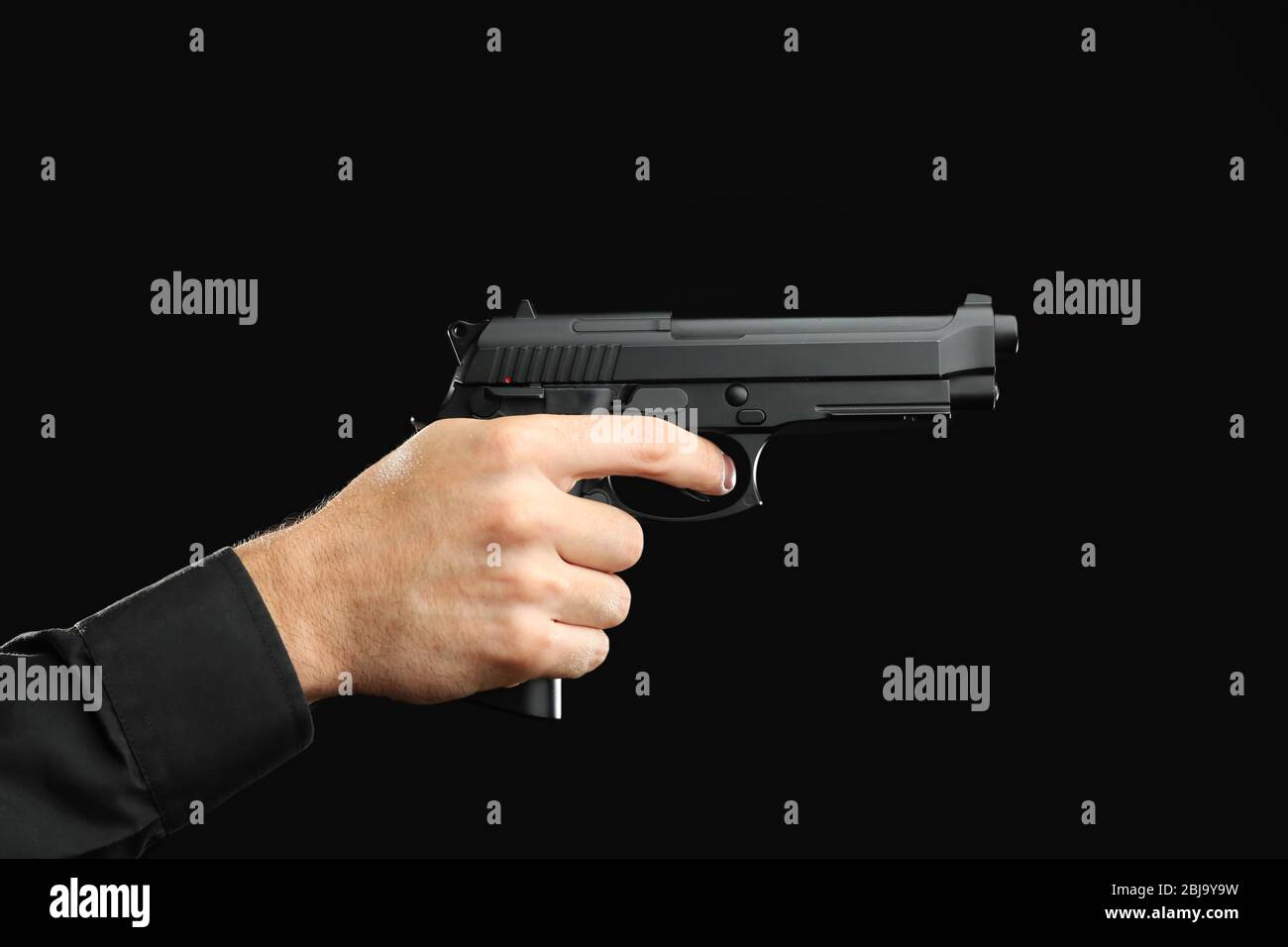 Man's hand holding gun on black background Stock Photo - Alamy