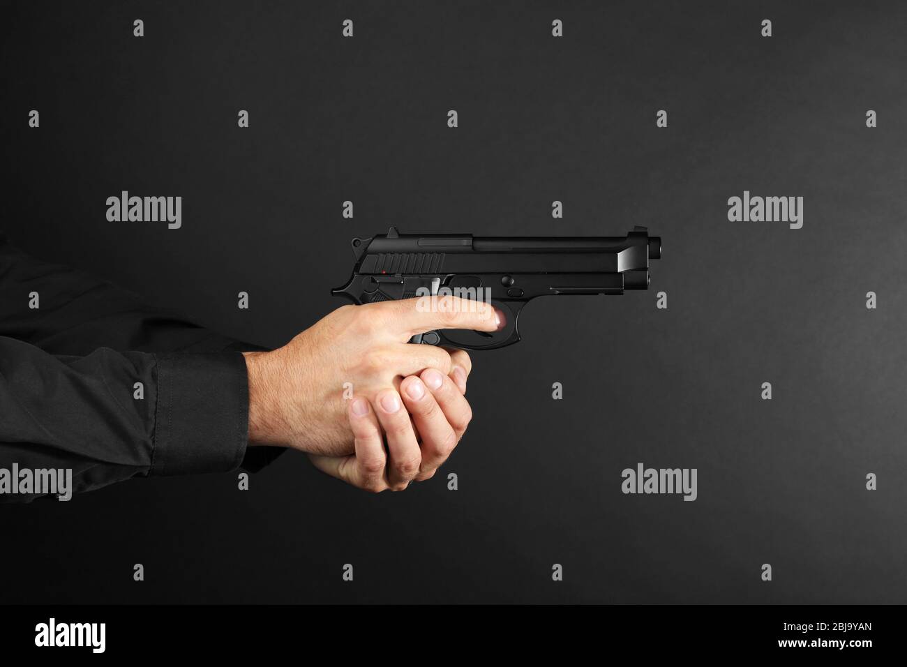 Man's hands holding gun on black background Stock Photo - Alamy