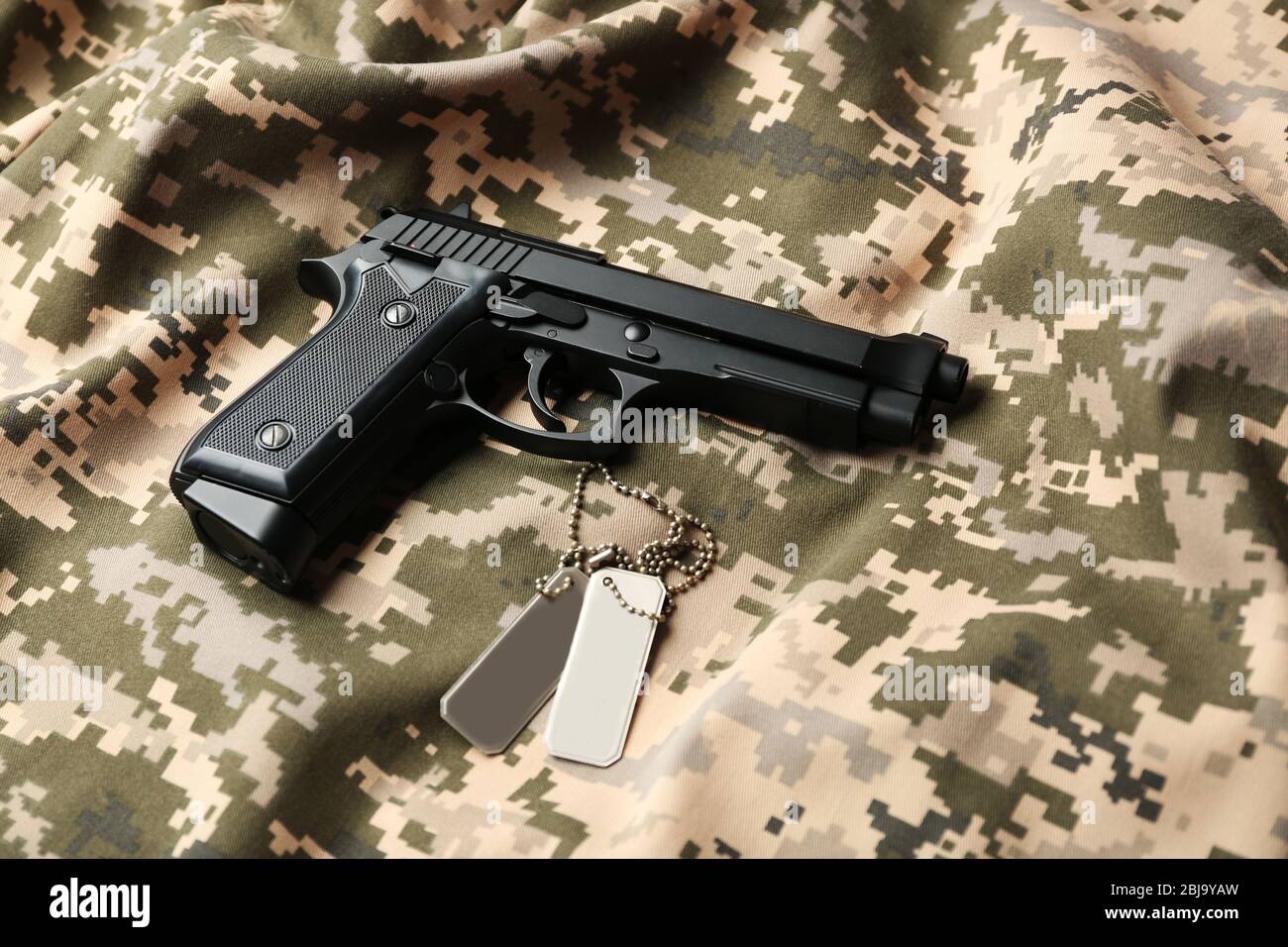 Gun and army token on khaki background Stock Photo - Alamy
