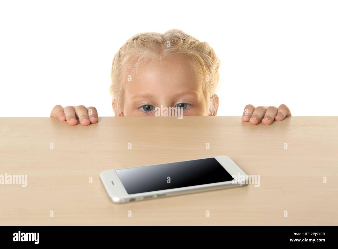 Funny little girl hiding behind table and looking at mobile phone Stock ...