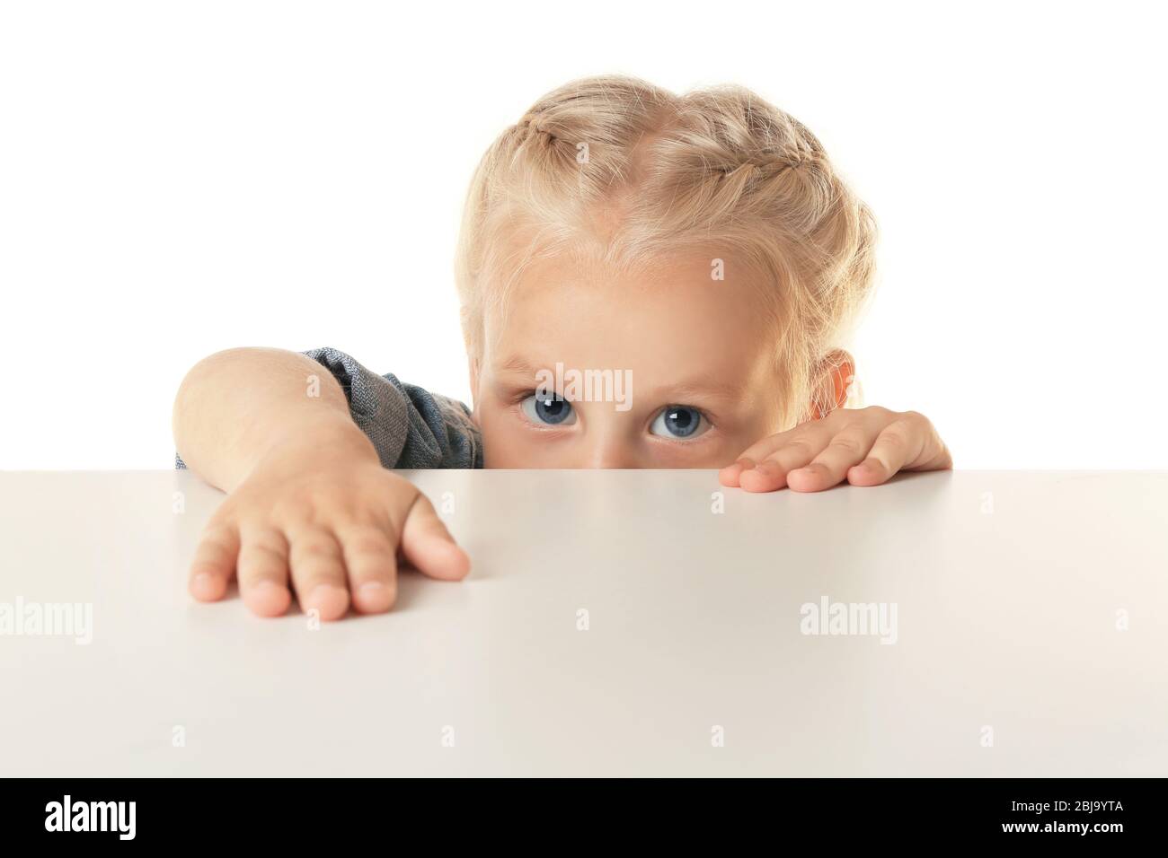 Funny little girl hiding behind white table Stock Photo - Alamy