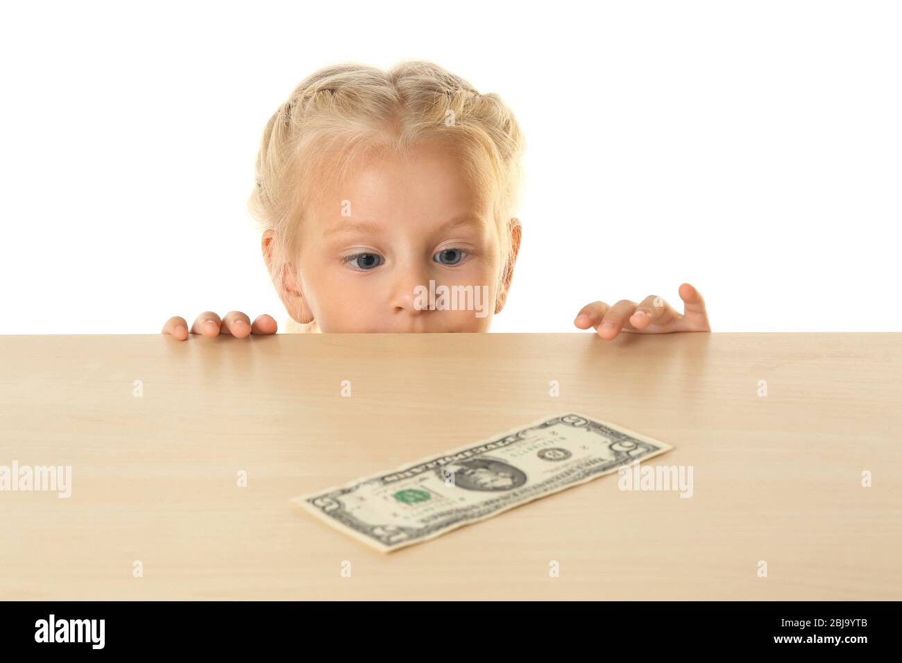 Funny little girl hiding behind table and looking at dollar Stock Photo ...