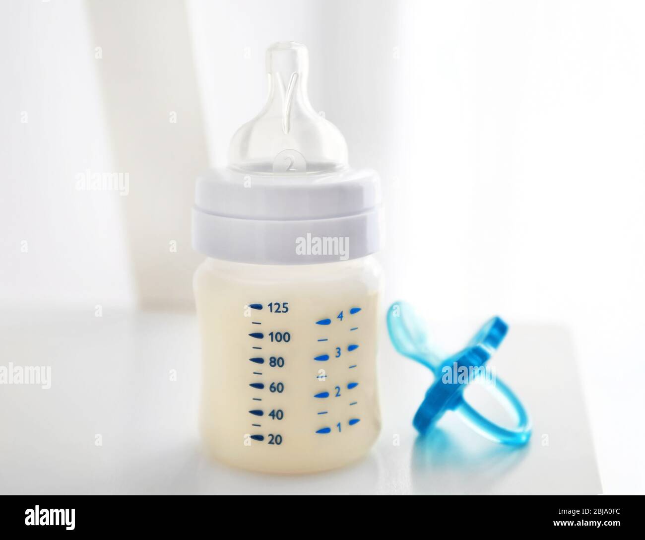 Baby milk bottle and pacifier on white background Stock Photo - Alamy