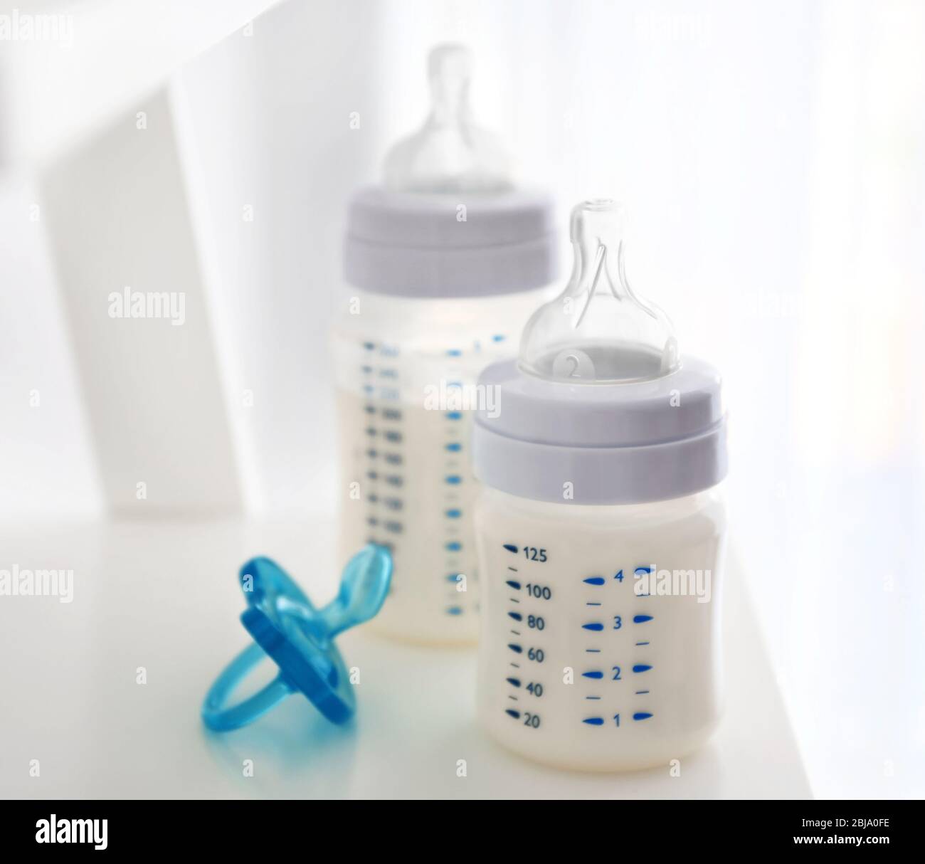Baby milk bottles and pacifier on white background Stock Photo - Alamy