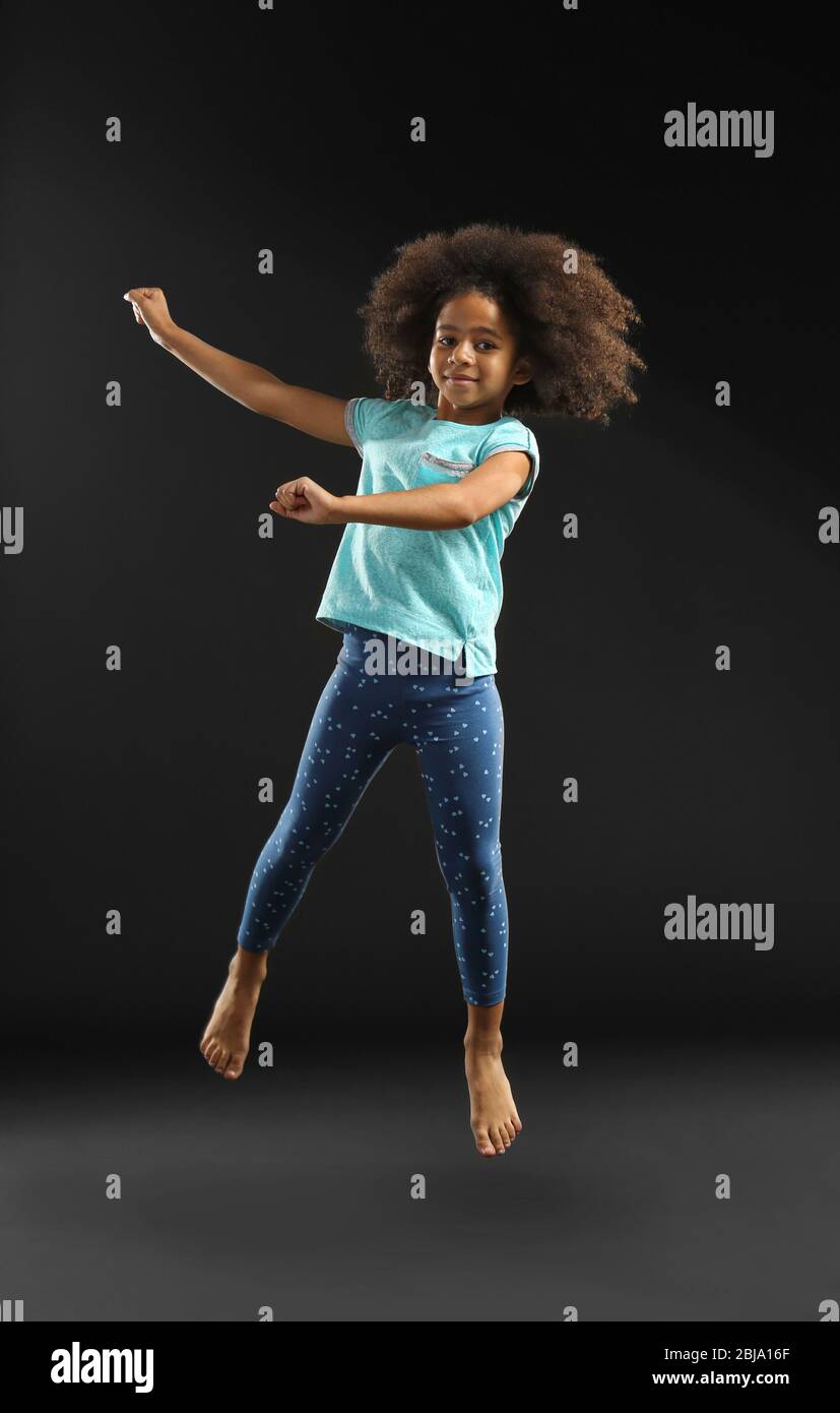 Happy African girl jumping on black background Stock Photo - Alamy