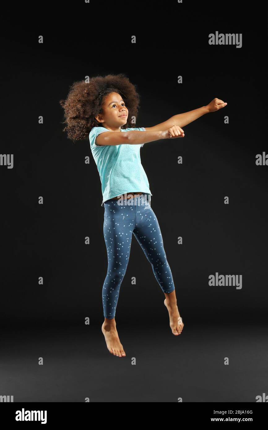 Happy African girl jumping on black background Stock Photo - Alamy