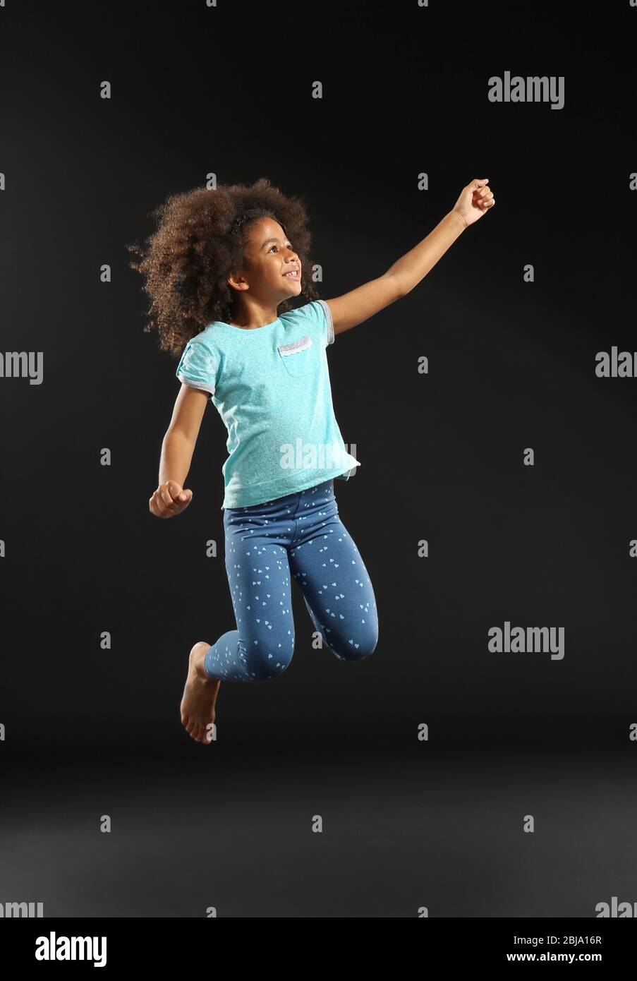 Happy African girl jumping on black background Stock Photo - Alamy