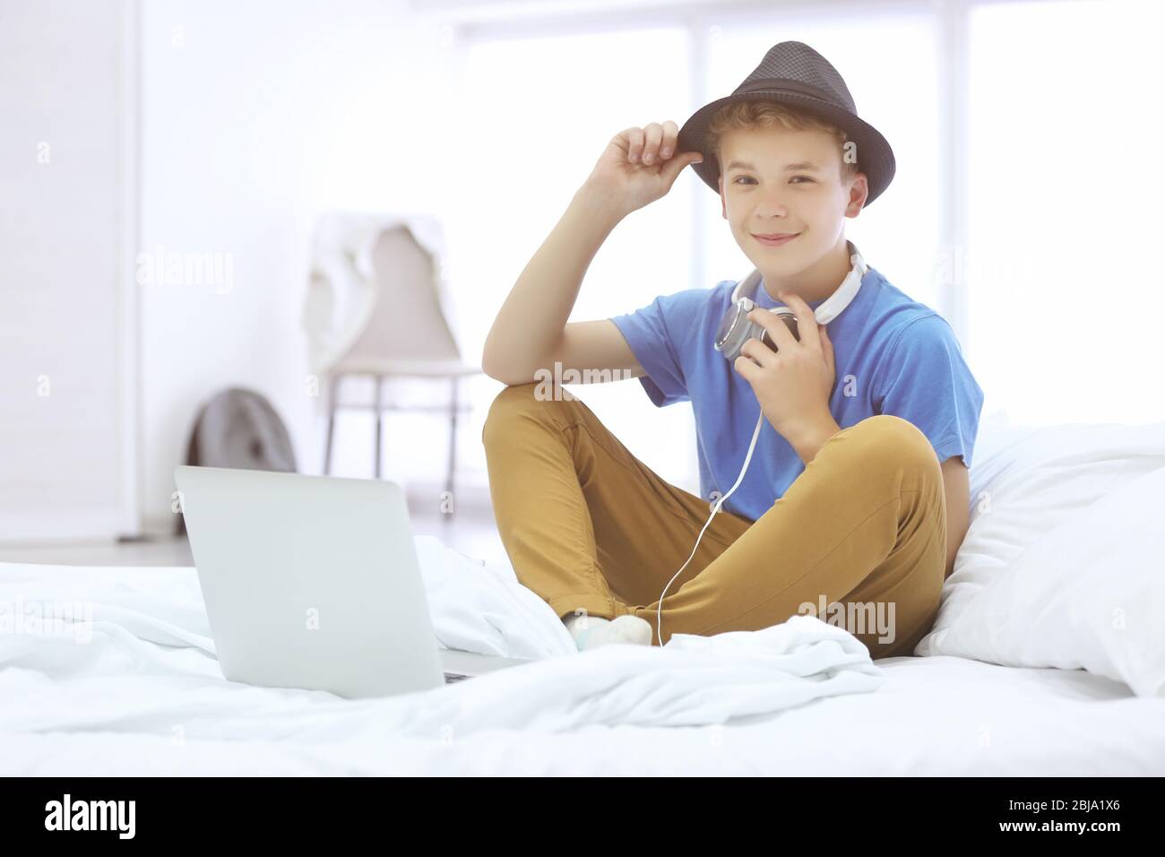 Boy sitting with computer on bed Stock Photo - Alamy