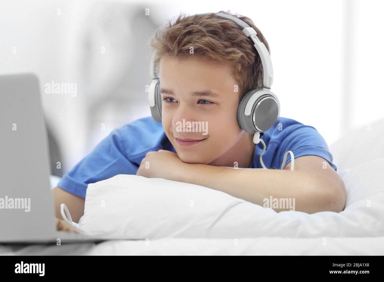 Boy laying with computer on bed Stock Photo - Alamy