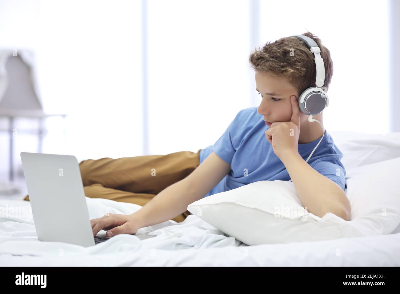 Boy laying with computer on bed Stock Photo - Alamy