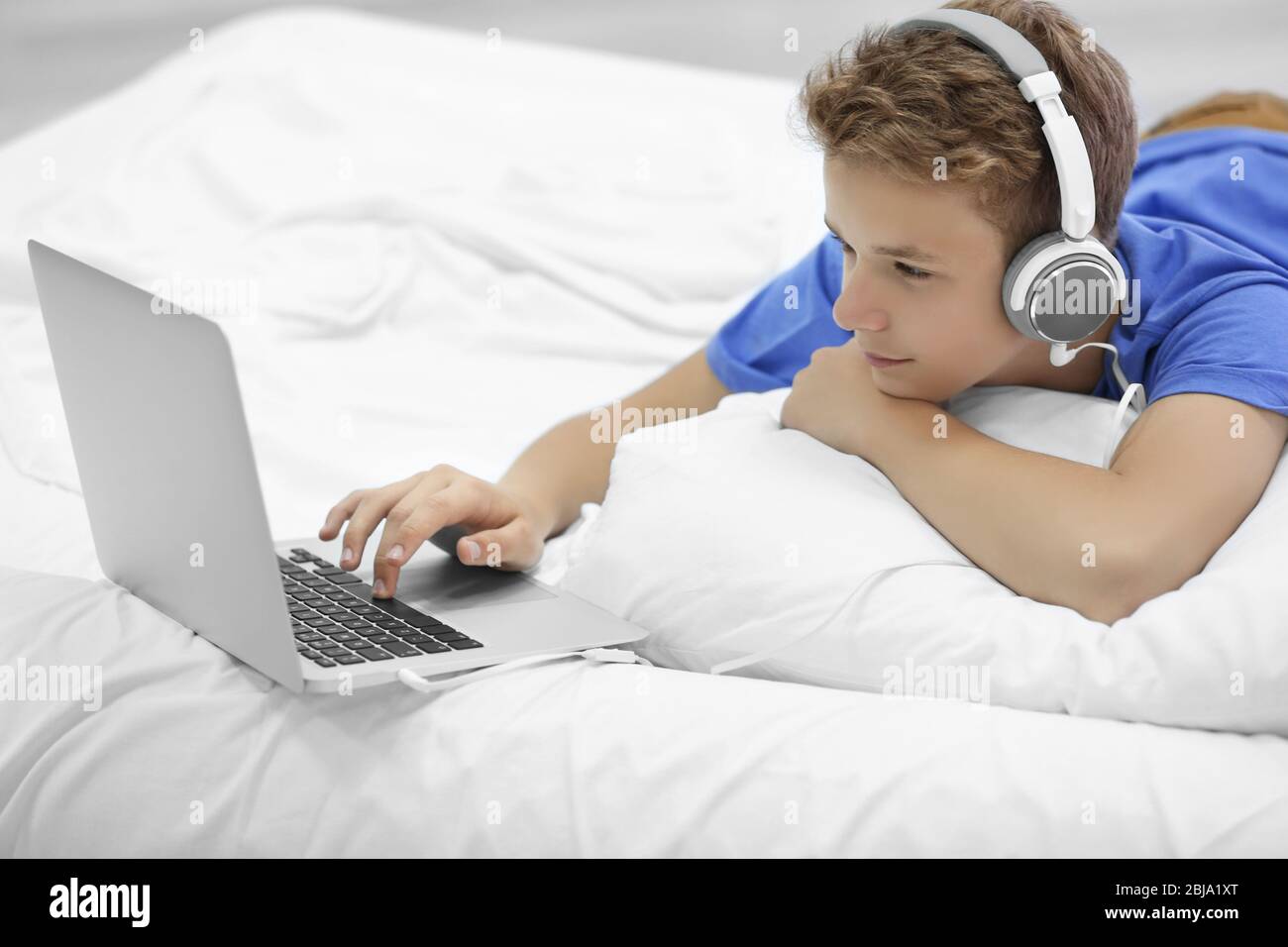 Boy laying with computer on bed Stock Photo - Alamy