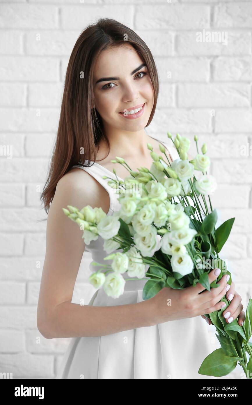 Beautiful Young Woman Holding Bouquet On White Brick Wall Background