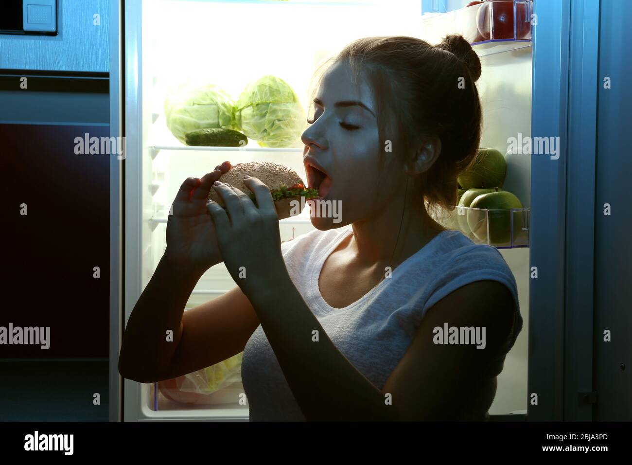 Beautiful girl eating sandwich at night. Unhealthy food concept Stock ...