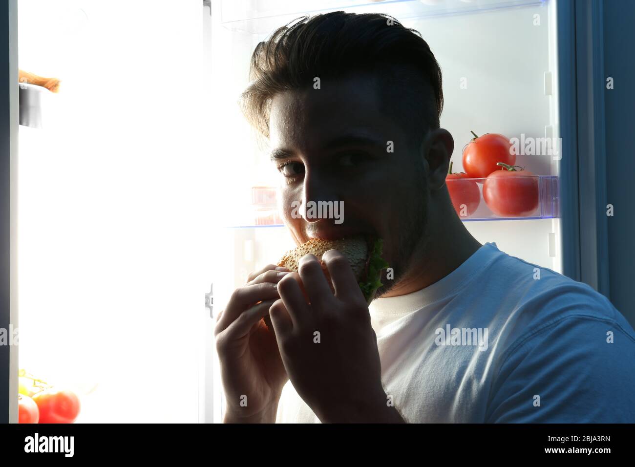 Handsome man eating sandwich in kitchen. Unhealthy food concept Stock ...