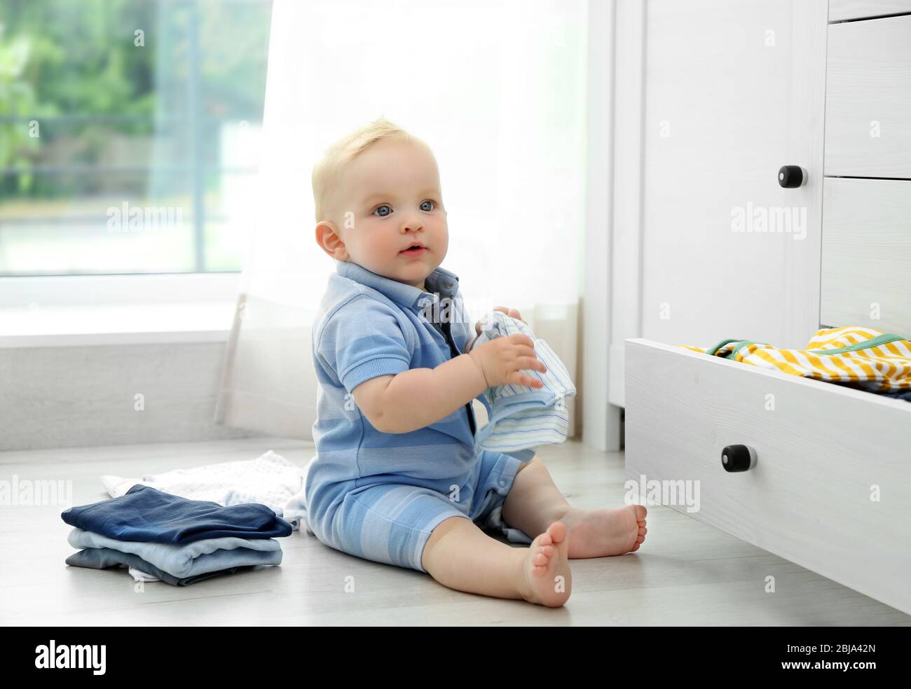 Baby throwing up clothes from wooden chest Stock Photo - Alamy