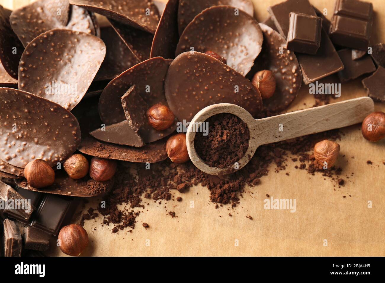 Chocolate chips and spoon with cocoa powder on parchment background ...