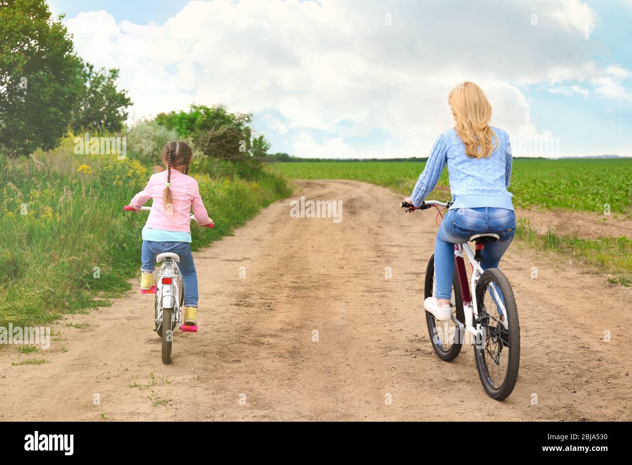 Mother with daughter riding bikes on country road Stock Photo - Alamy
