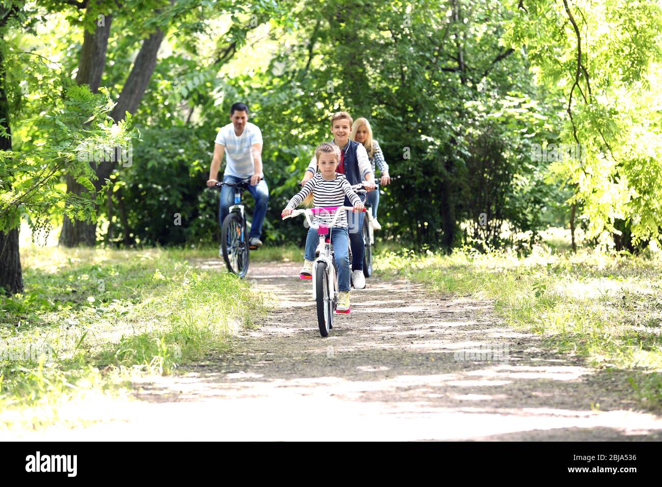 Happy family on bike ride in park Stock Photo - Alamy