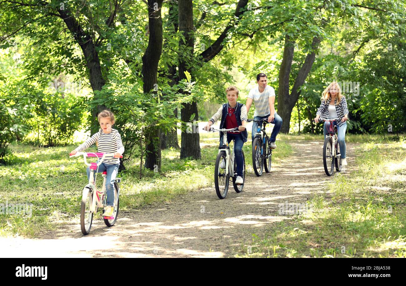 Happy family on bike ride in park Stock Photo - Alamy