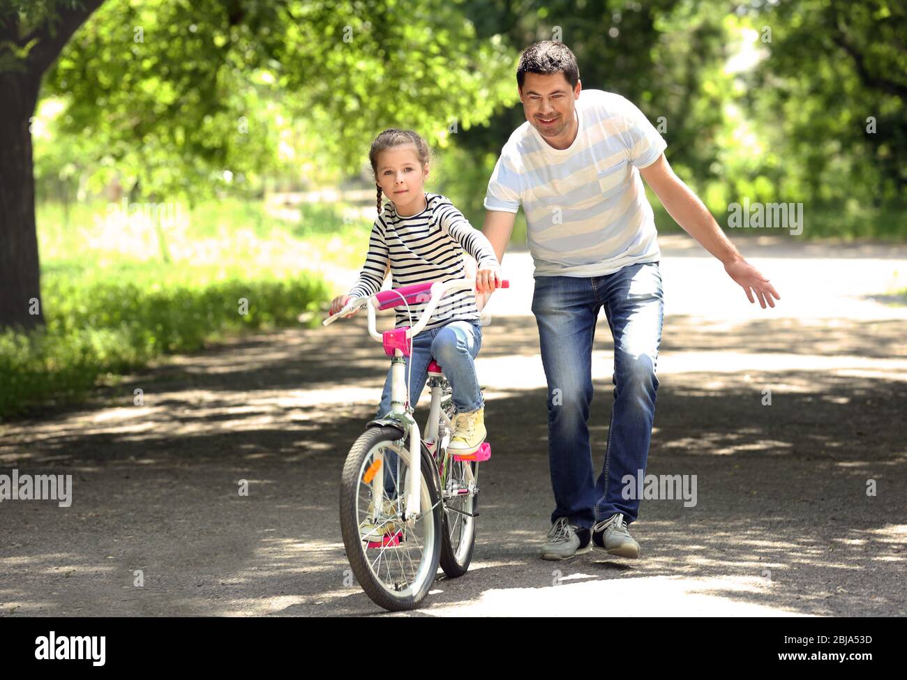 Father teaching daughter ride bike in park Stock Photo - Alamy
