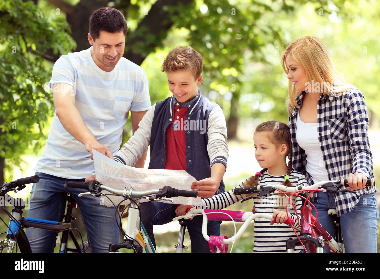 Happy family with map on bike ride in park Stock Photo - Alamy