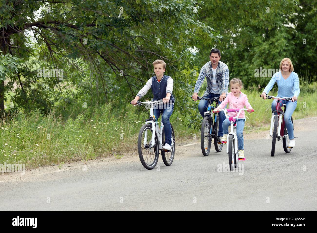 Happy family riding bikes on road Stock Photo - Alamy