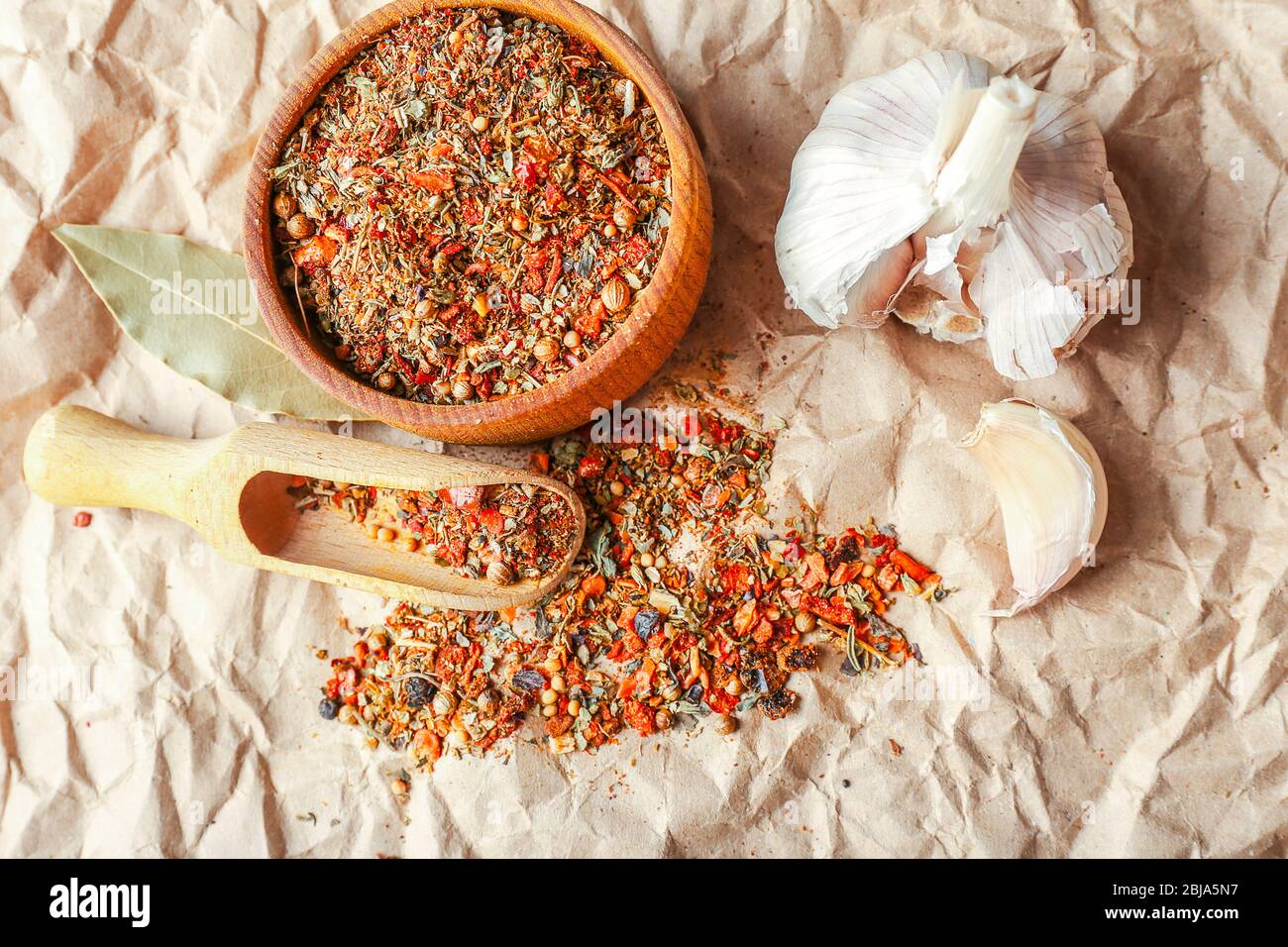 Mixed spices in wooden scoop and bowl on parchment background Stock Photo - Alamy