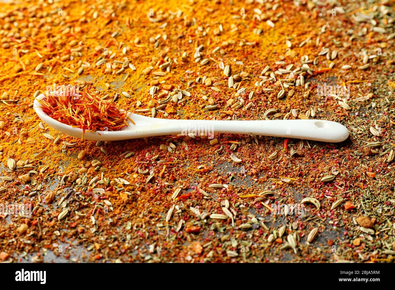 Saffron in white spoon on mixed spices background Stock Photo - Alamy