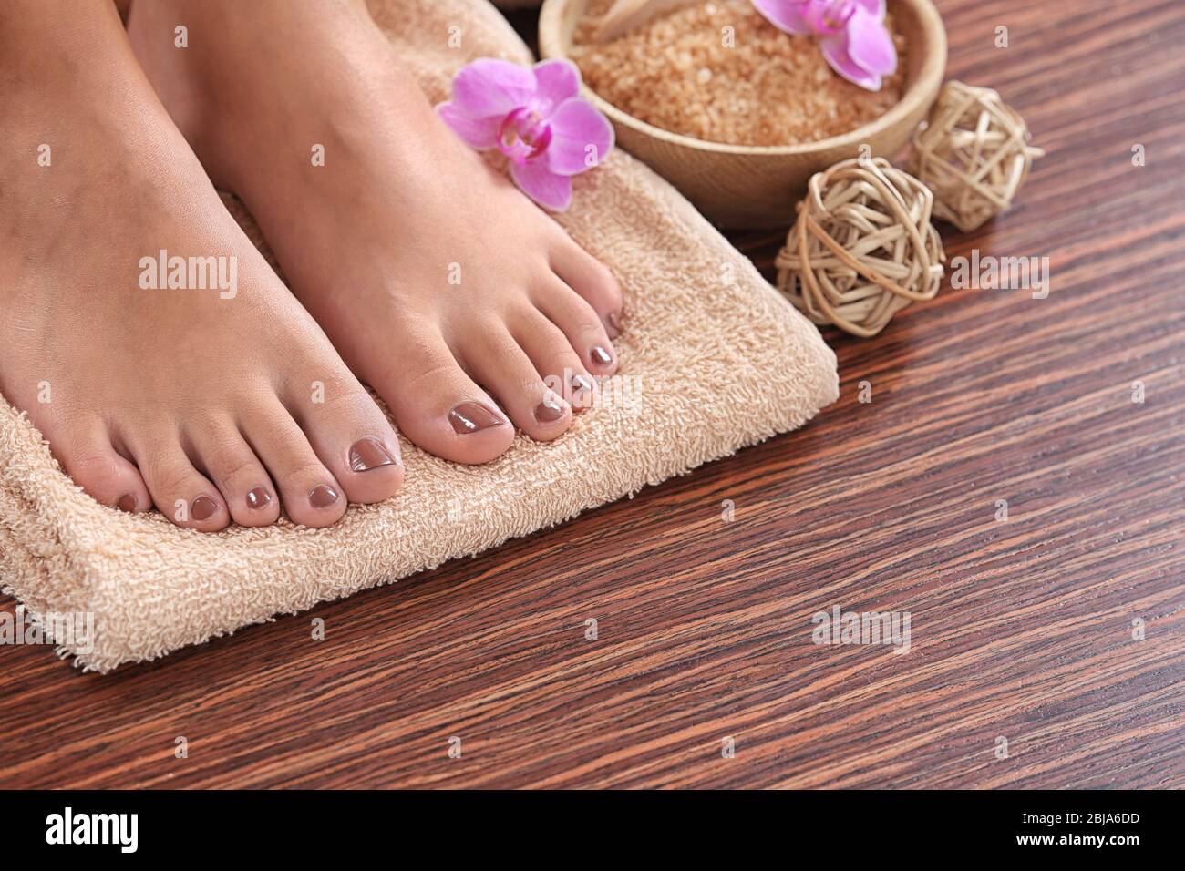 Female feet with brown pedicure and flowers on towel Stock Photo - Alamy