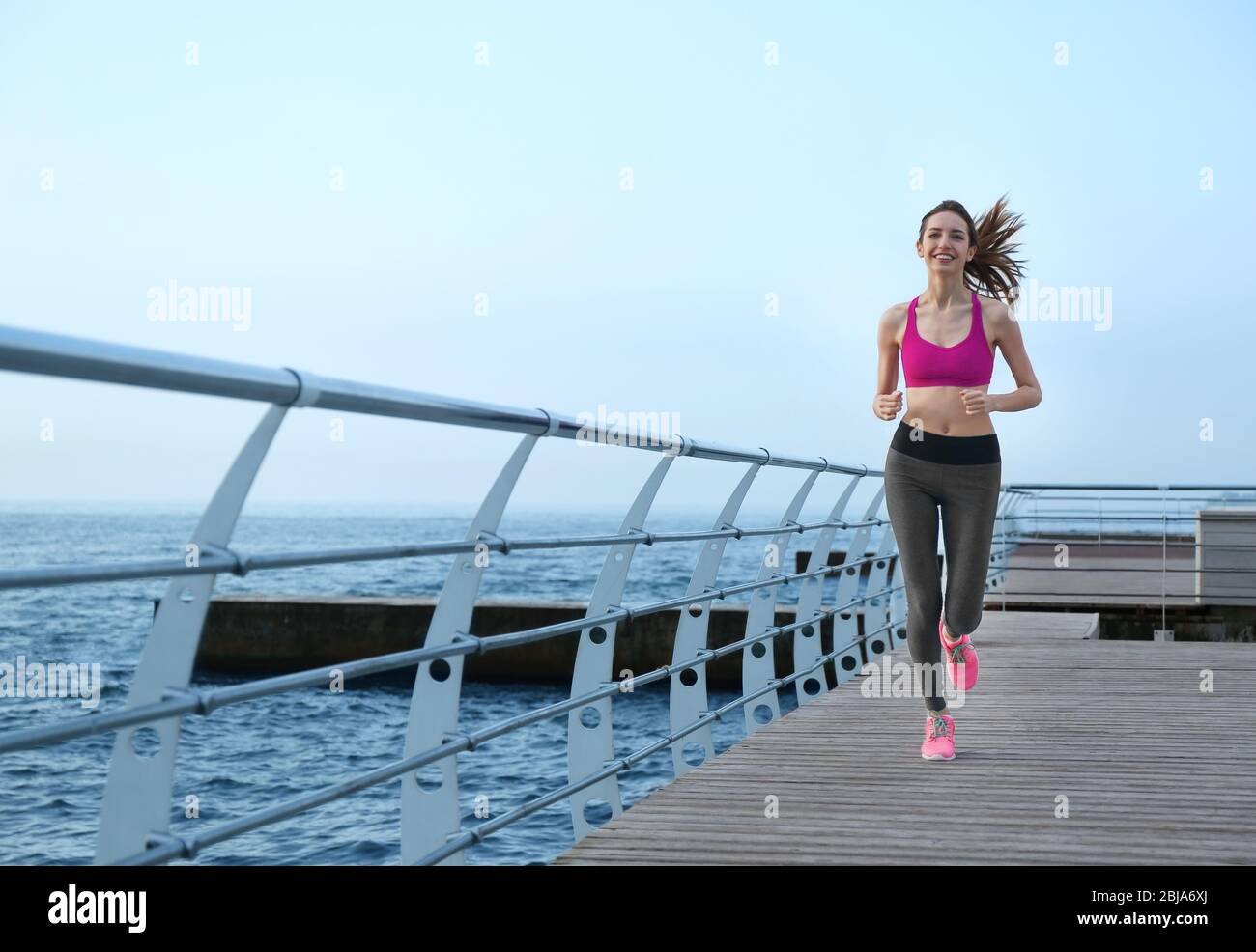 Young woman running on pier Stock Photo - Alamy