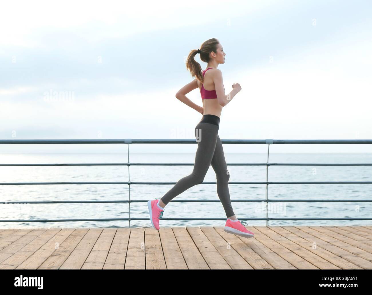 Young woman running on pier Stock Photo - Alamy