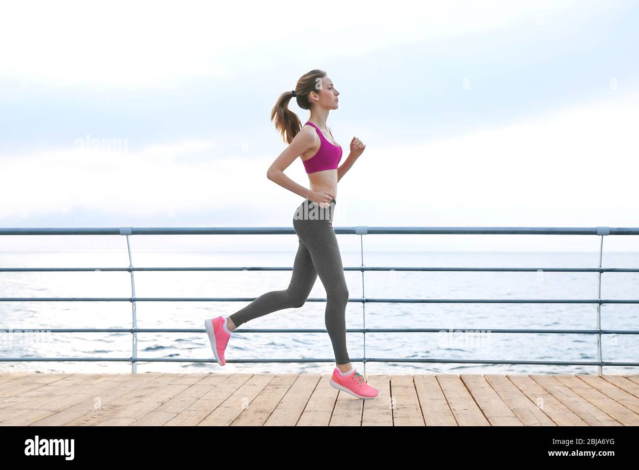 Young woman running on pier Stock Photo - Alamy
