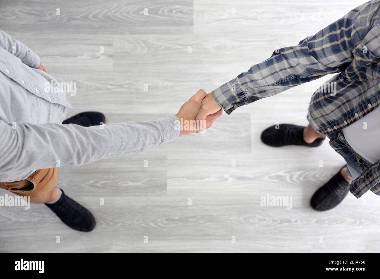 Men shaking hands in room, top view Stock Photo - Alamy