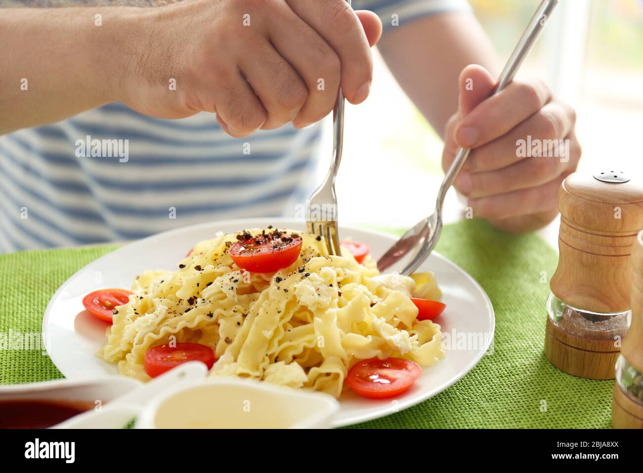 Man eating delicious pasta in restaurant Stock Photo - Alamy