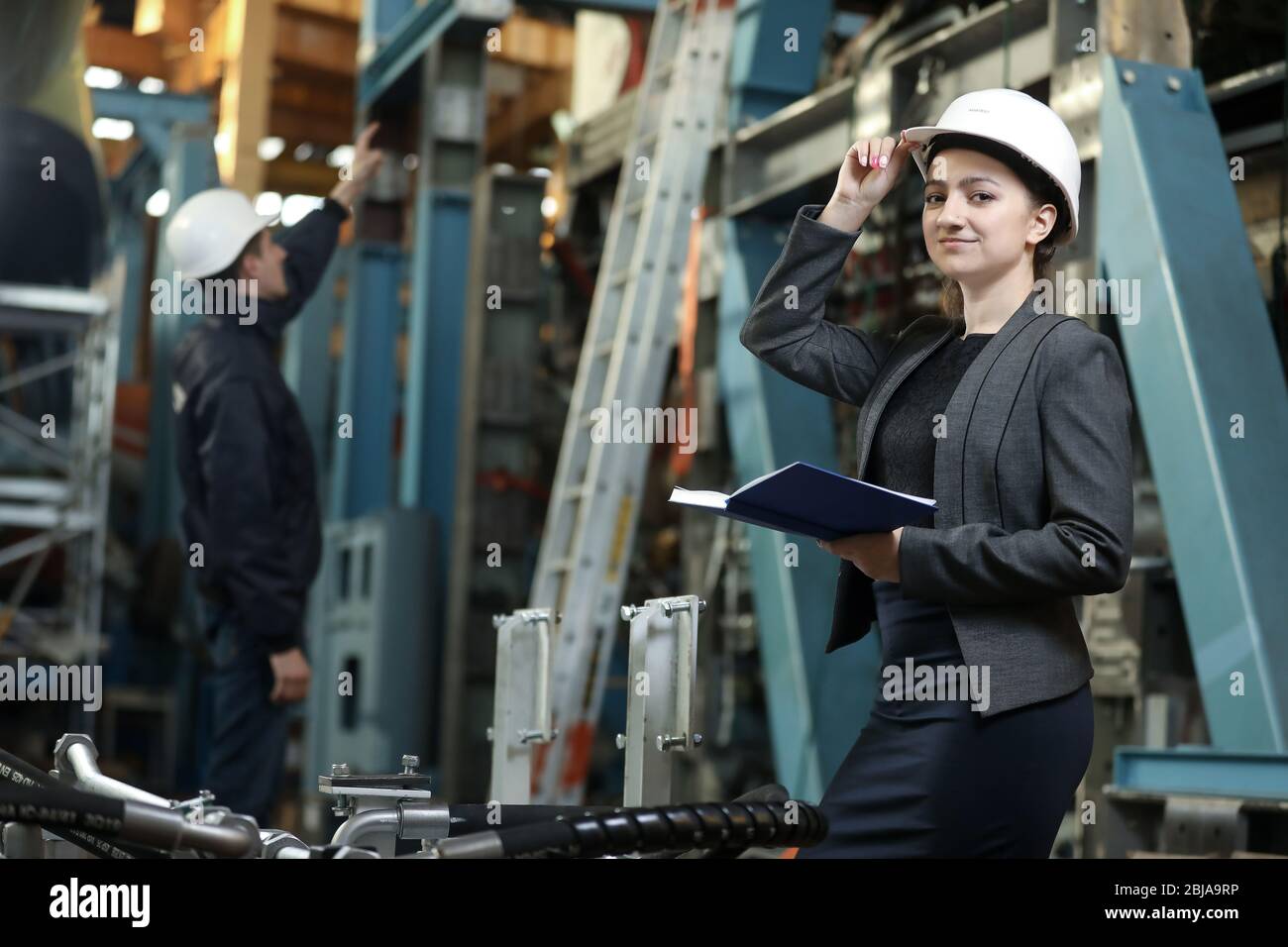 Portrait of a female factory manager in a white hard hat and business ...